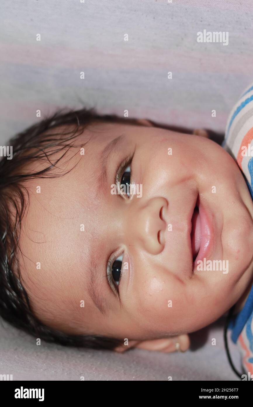 Close-up of An indian little newborn innocent male baby smiling looking ...