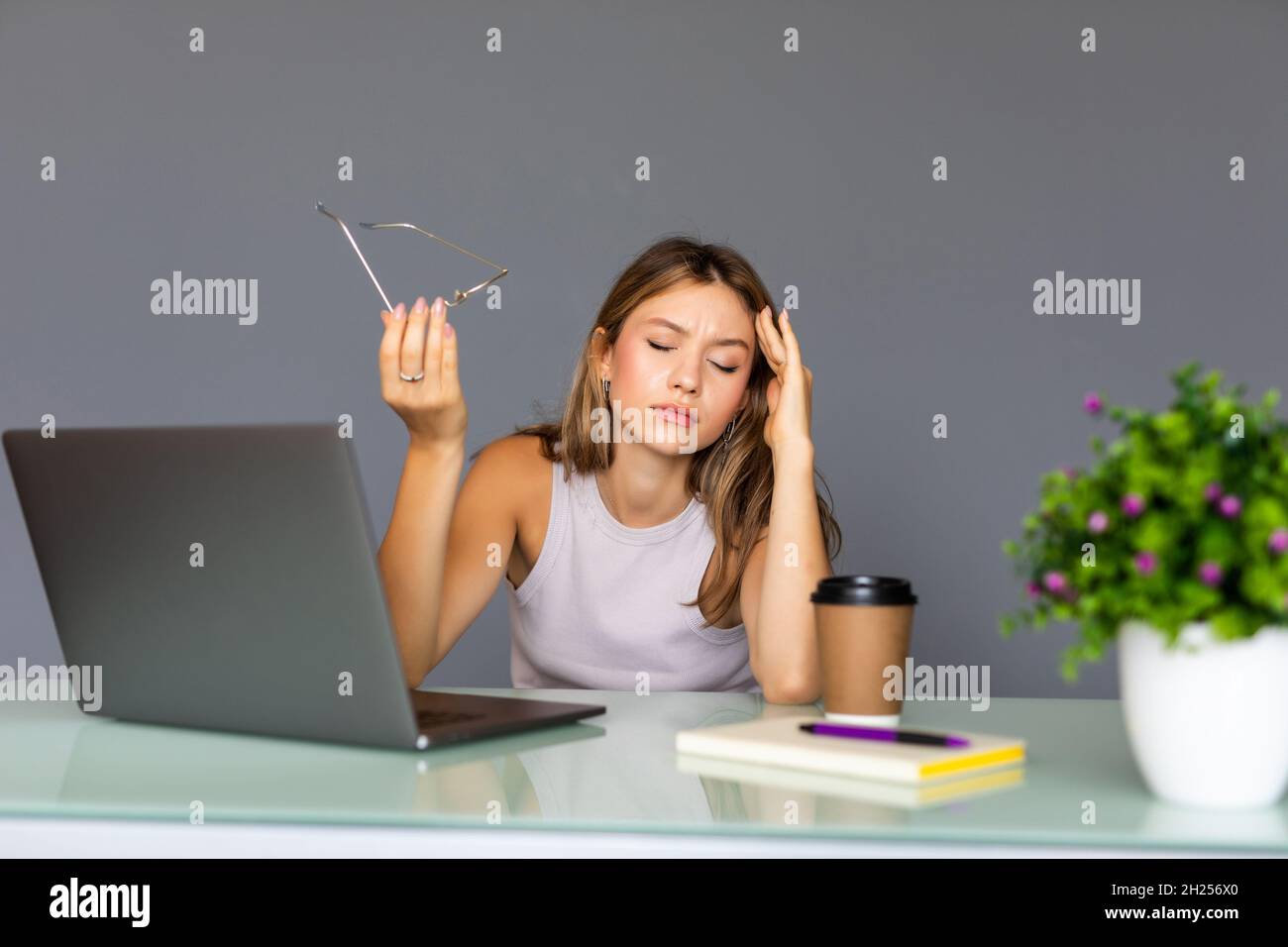 Bored young woman in the office working with a laptop and staring at ...