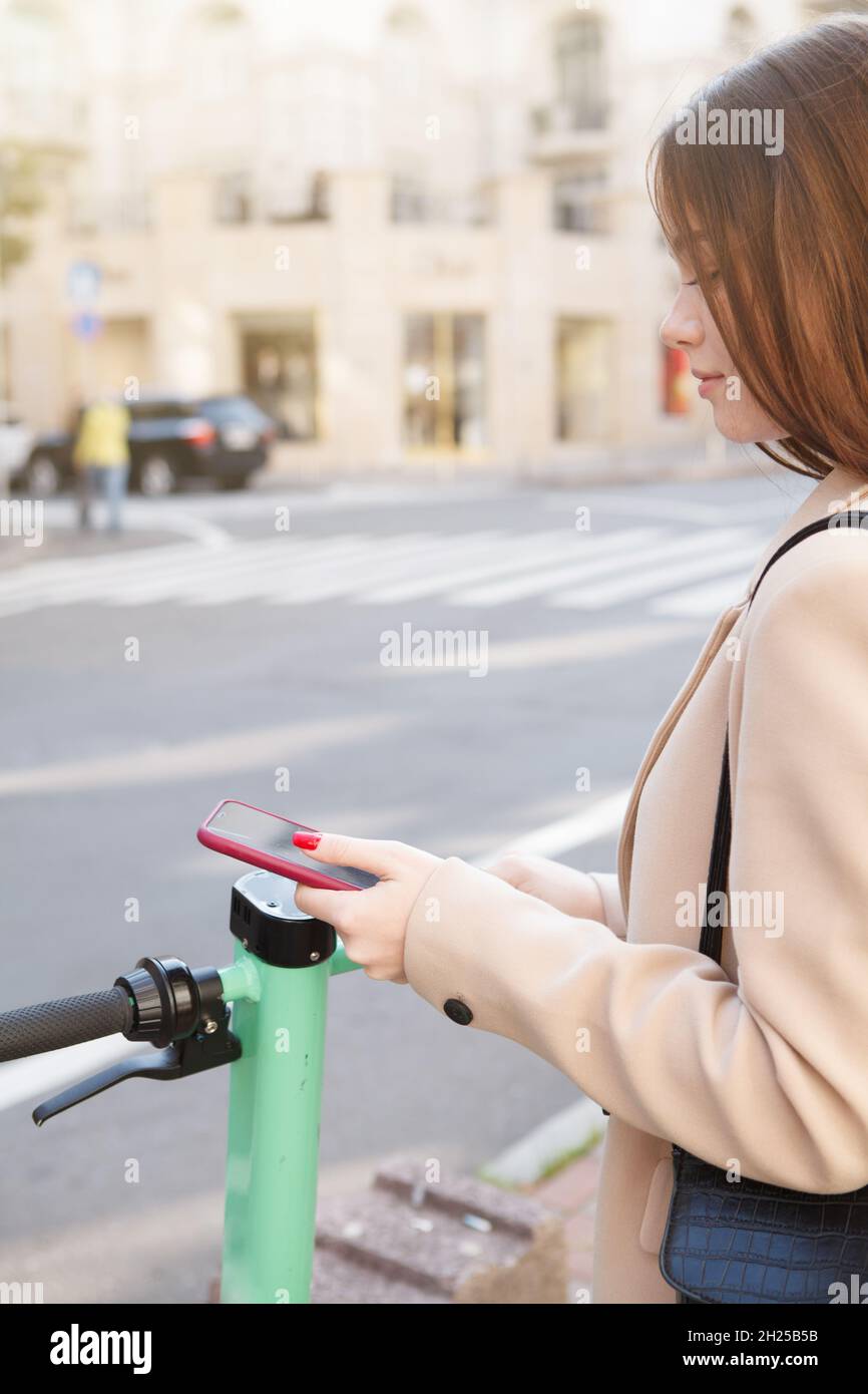 Vertical cropped shot of a woman scanning qr-code of electric scooter ...