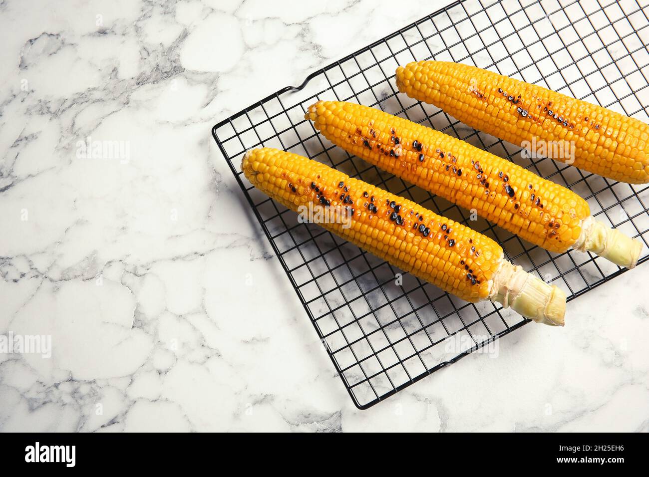 Cooling rack with grilled corn cobs on marble background, top view ...