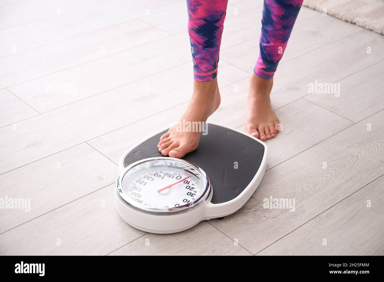 Woman measuring her weight using scales on floor Stock Photo - Alamy