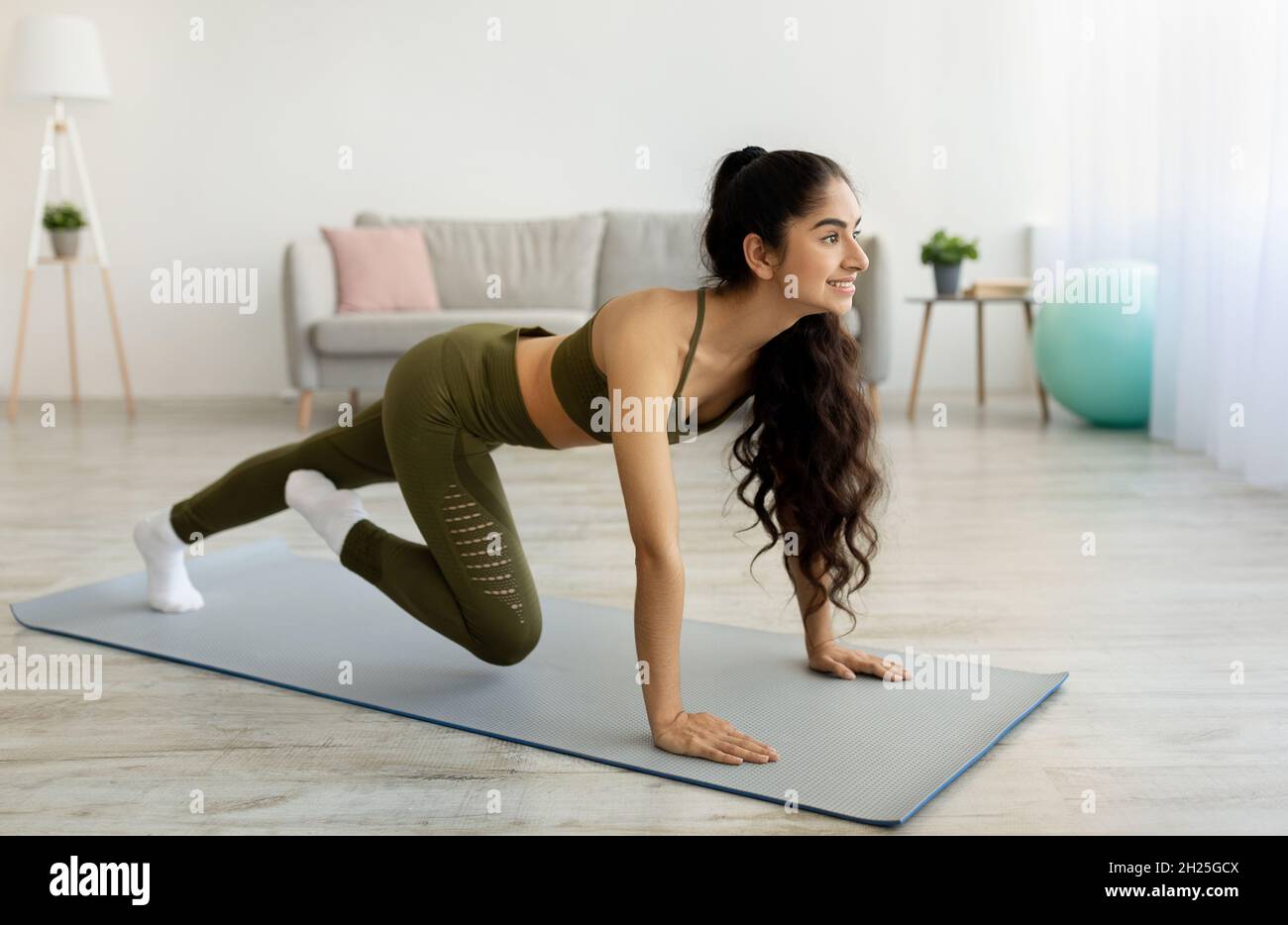 Beautiful young Indian woman doing strength exercises, training her abs ...