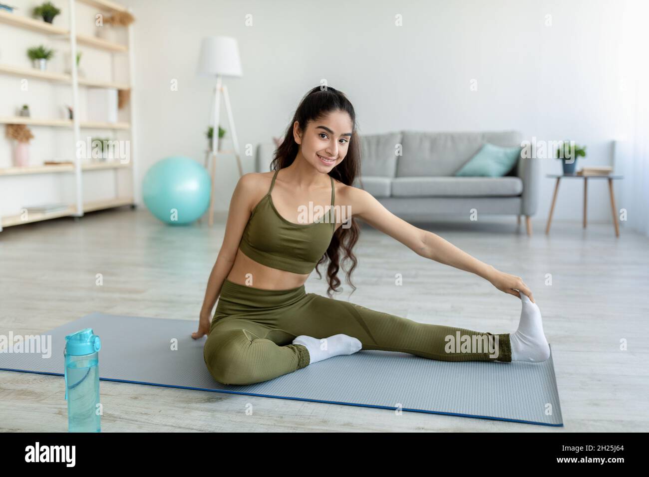 Pretty young Indian woman stretching her legs, exercising during home ...