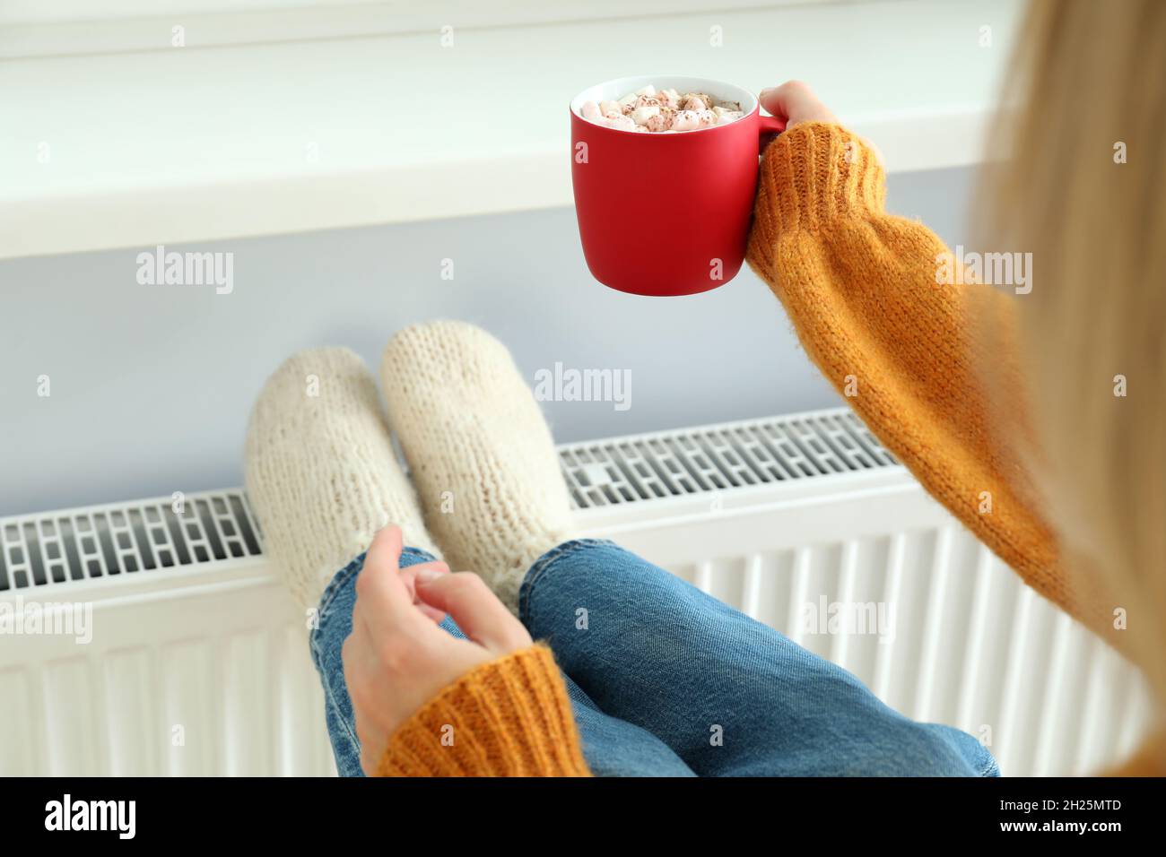 Concept of heating season with girl sitting near radiator Stock Photo ...