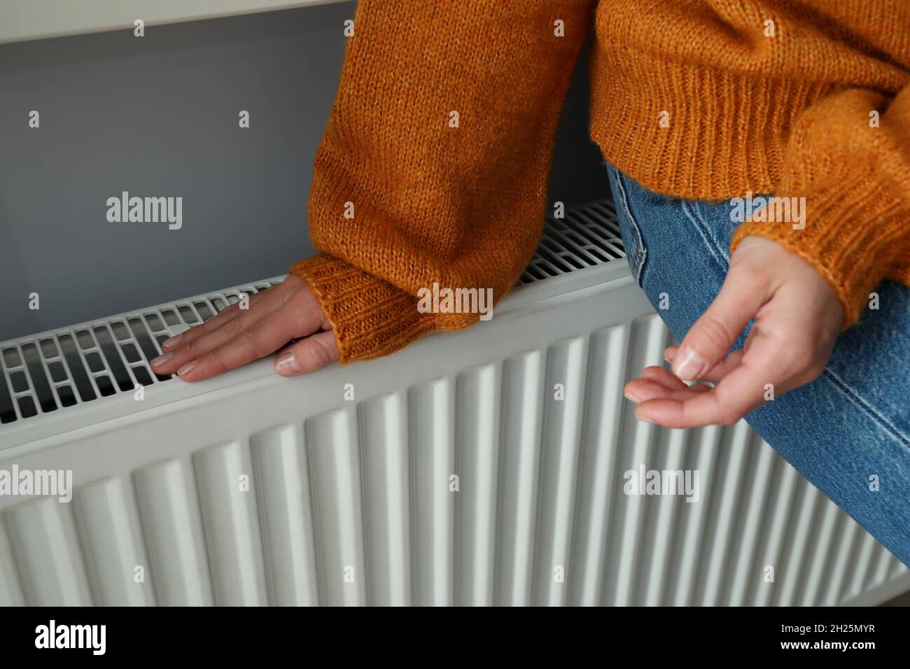 Concept of heating season with girl sitting on radiator Stock Photo - Alamy