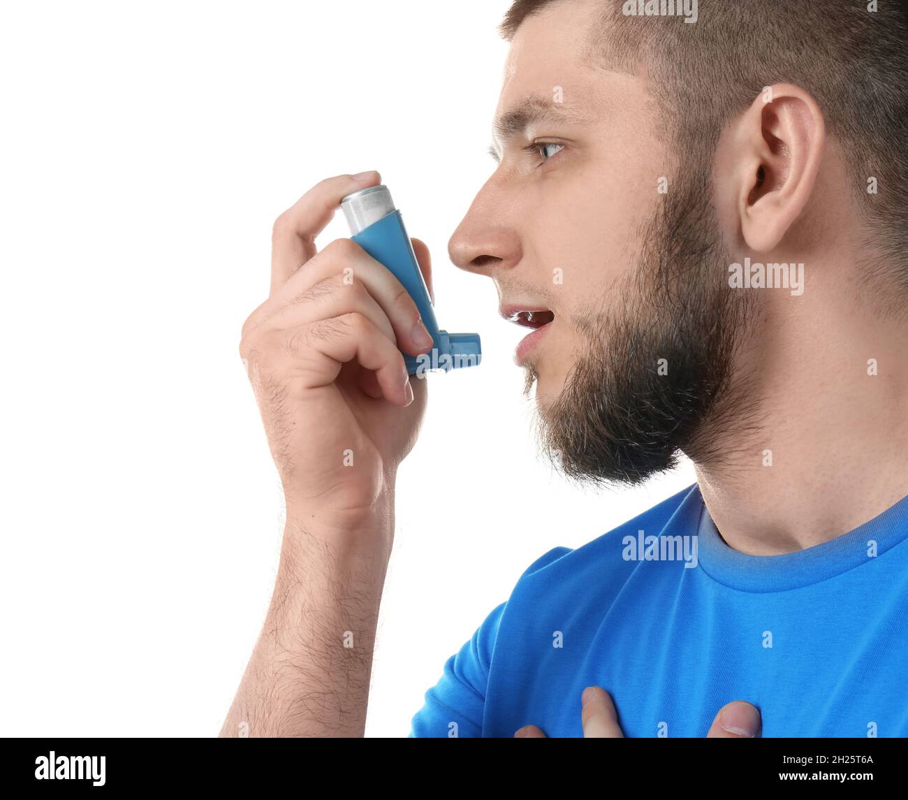 Young man using asthma inhaler on white background Stock Photo - Alamy