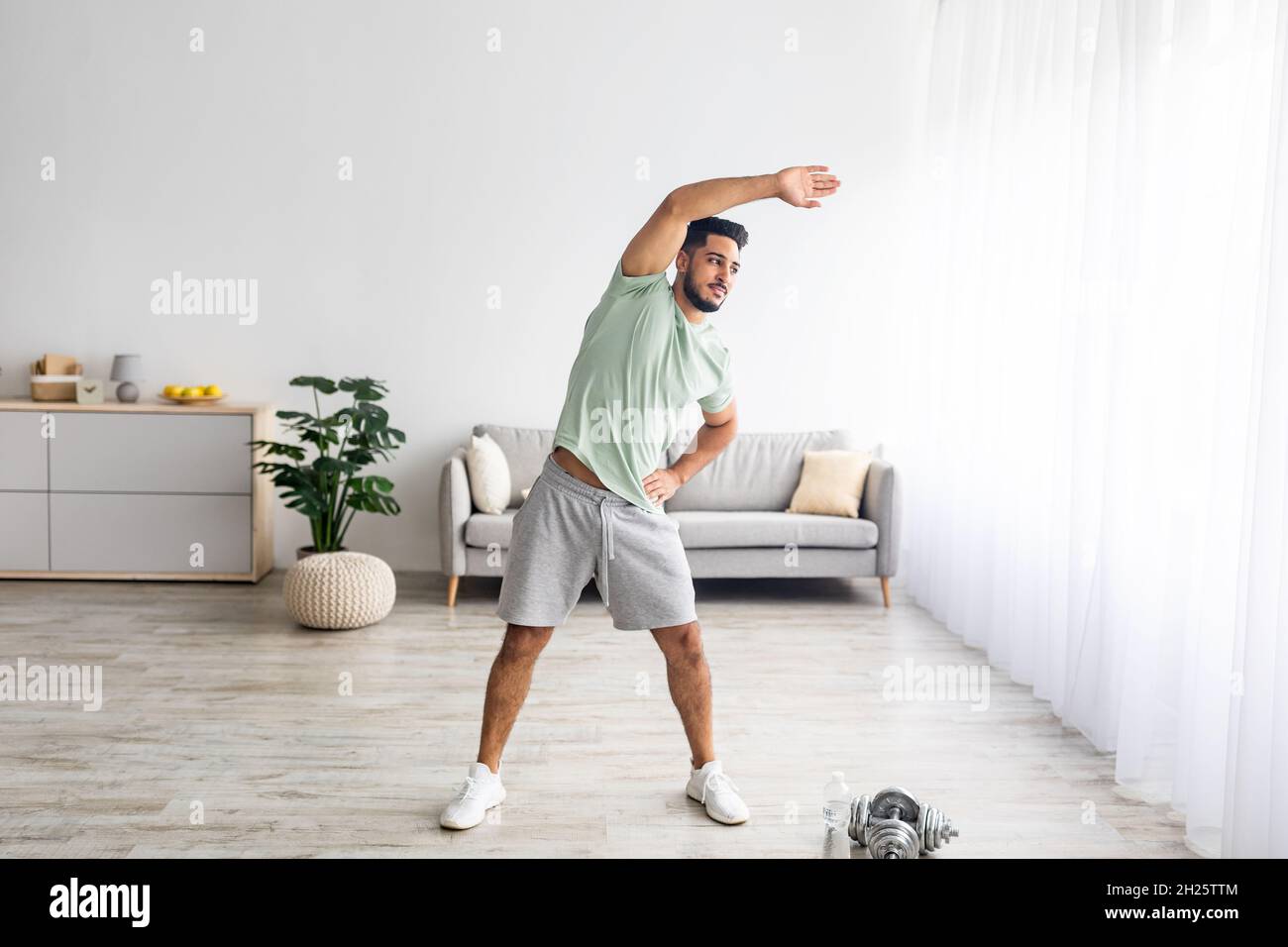 Full length of athletic young Arab man bending aside, doing exercises ...