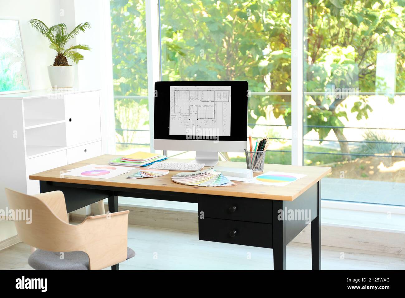 Designer's workplace with computer and paint color palette samples on ...