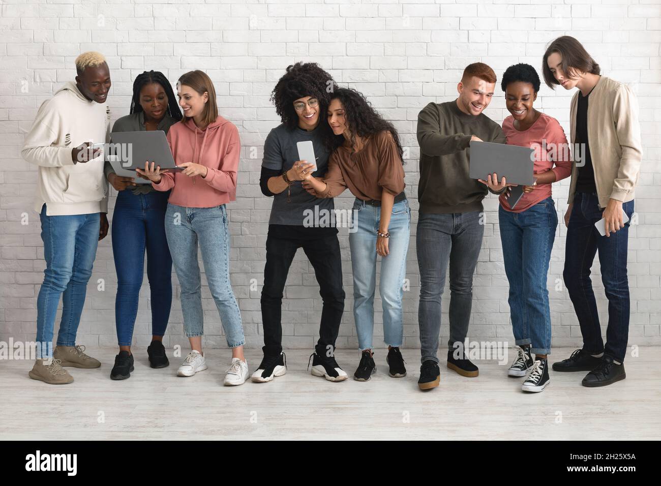 Cheerful multiracial millennials using gadgets while spending time ...