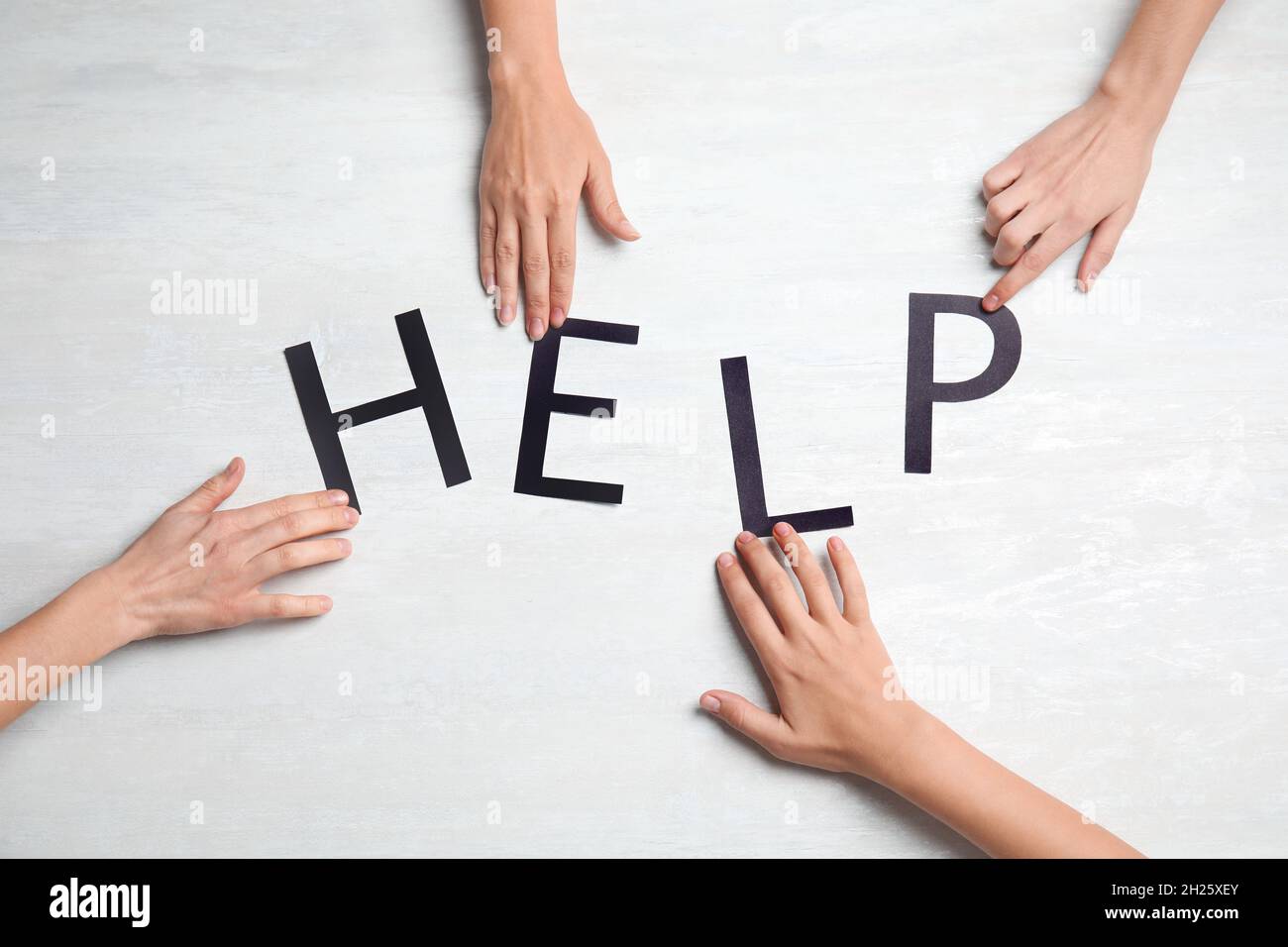 People making word "HELP" of letters on light background, top view ...