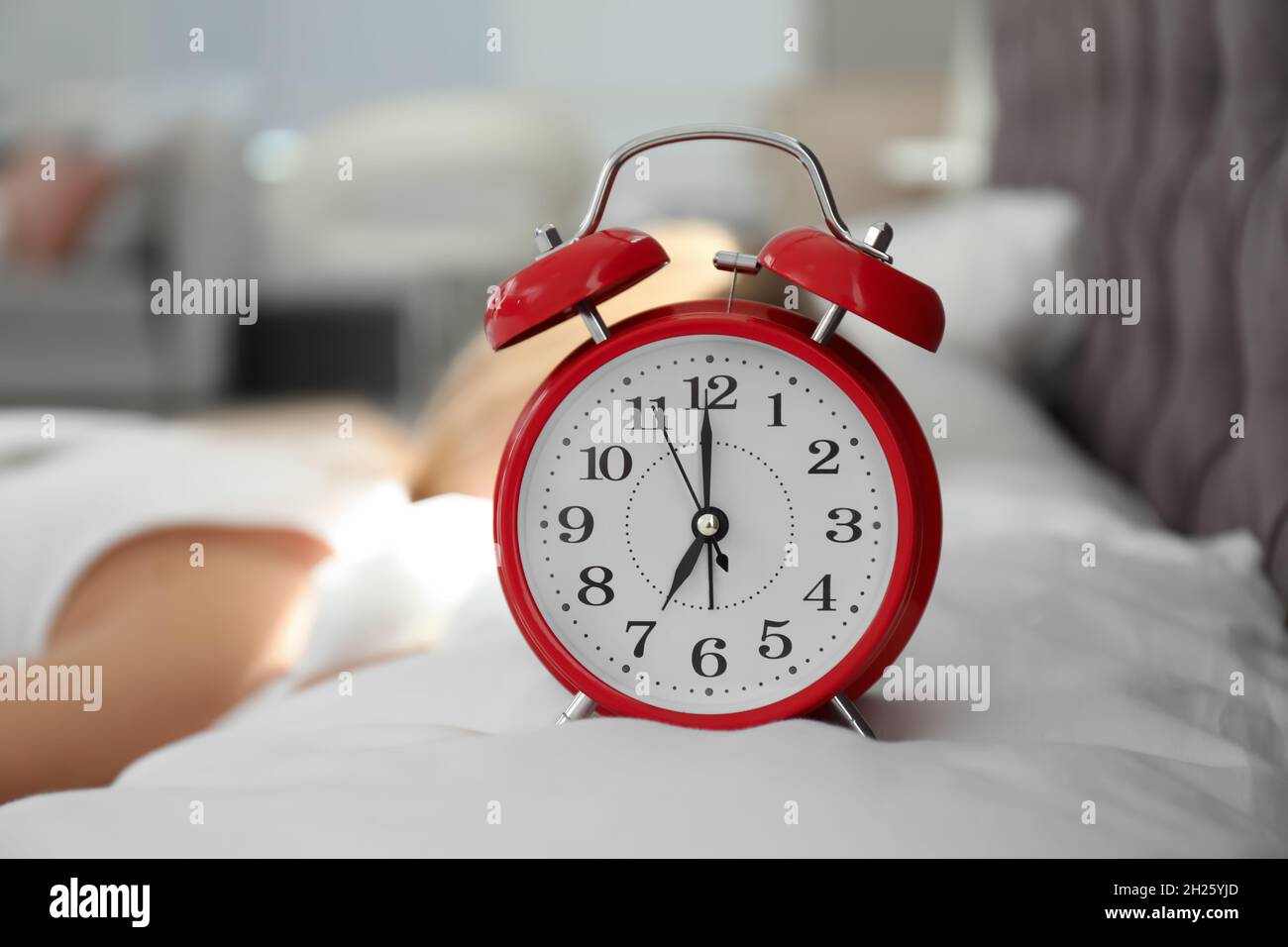 Analog alarm clock and blurred woman on background. Time of day Stock ...
