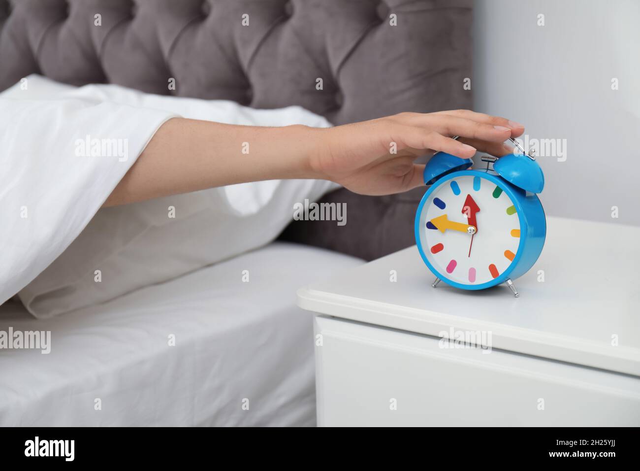 Man turning off alarm clock in bedroom Stock Photo - Alamy
