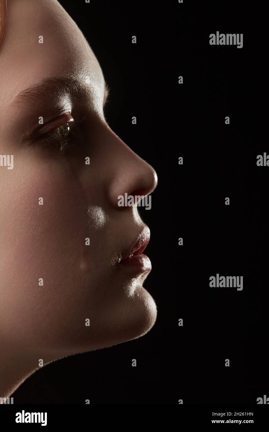 sad woman crying, looking aside on black background, closeup portrait ...