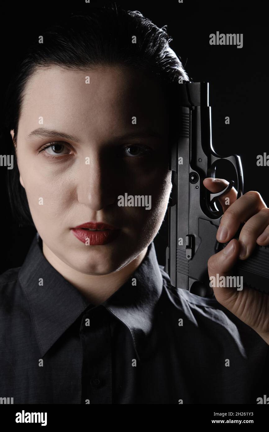 female portrait with gun closeup on black background closeup front view ...