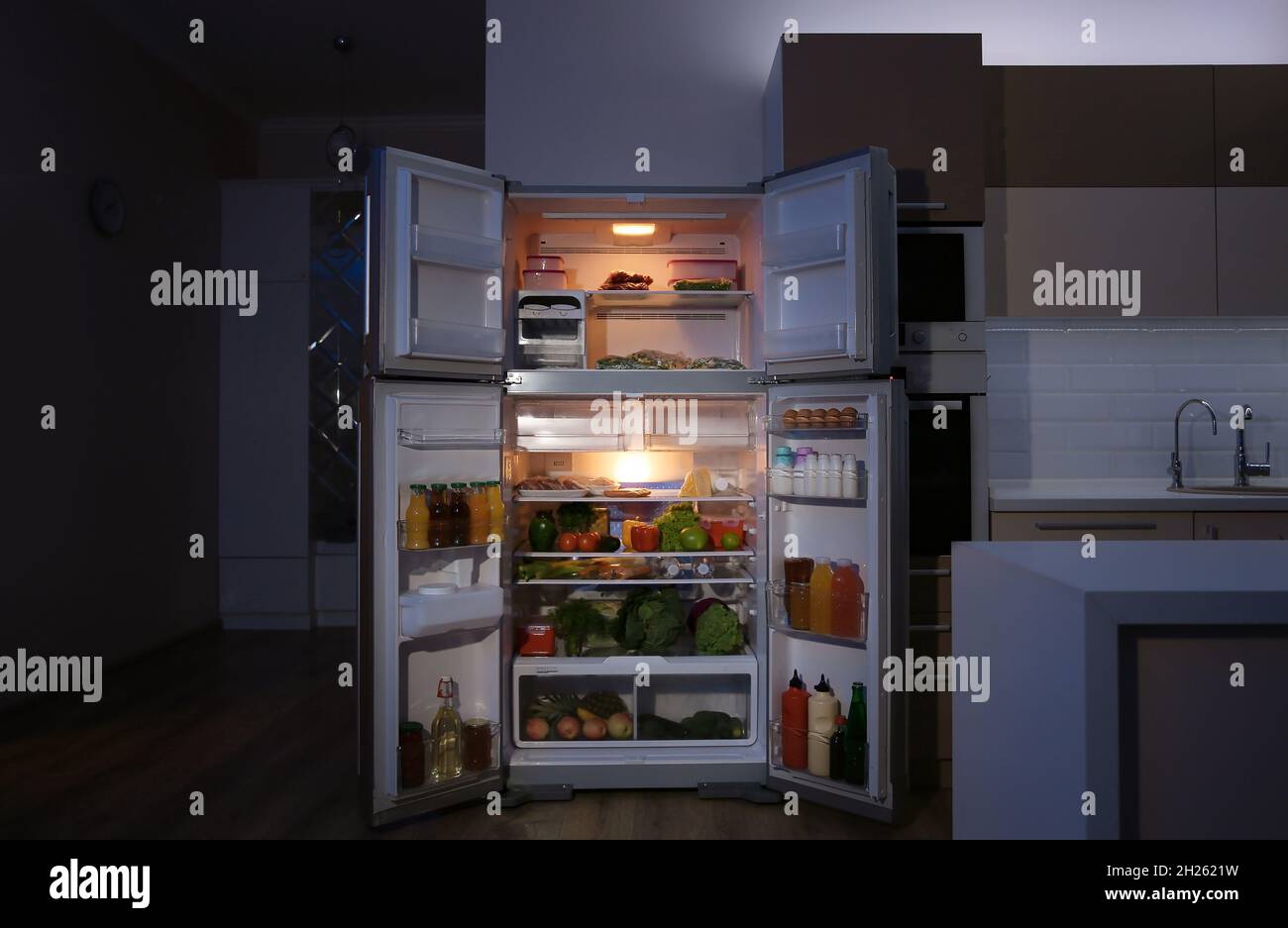 Open refrigerator filled with food in kitchen at night Stock Photo - Alamy