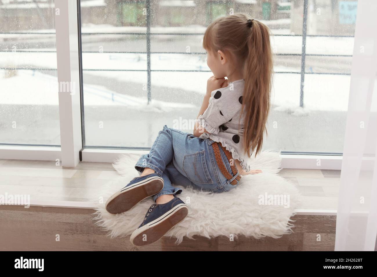 Lonely little girl sitting near window indoors. Autism concept Stock ...
