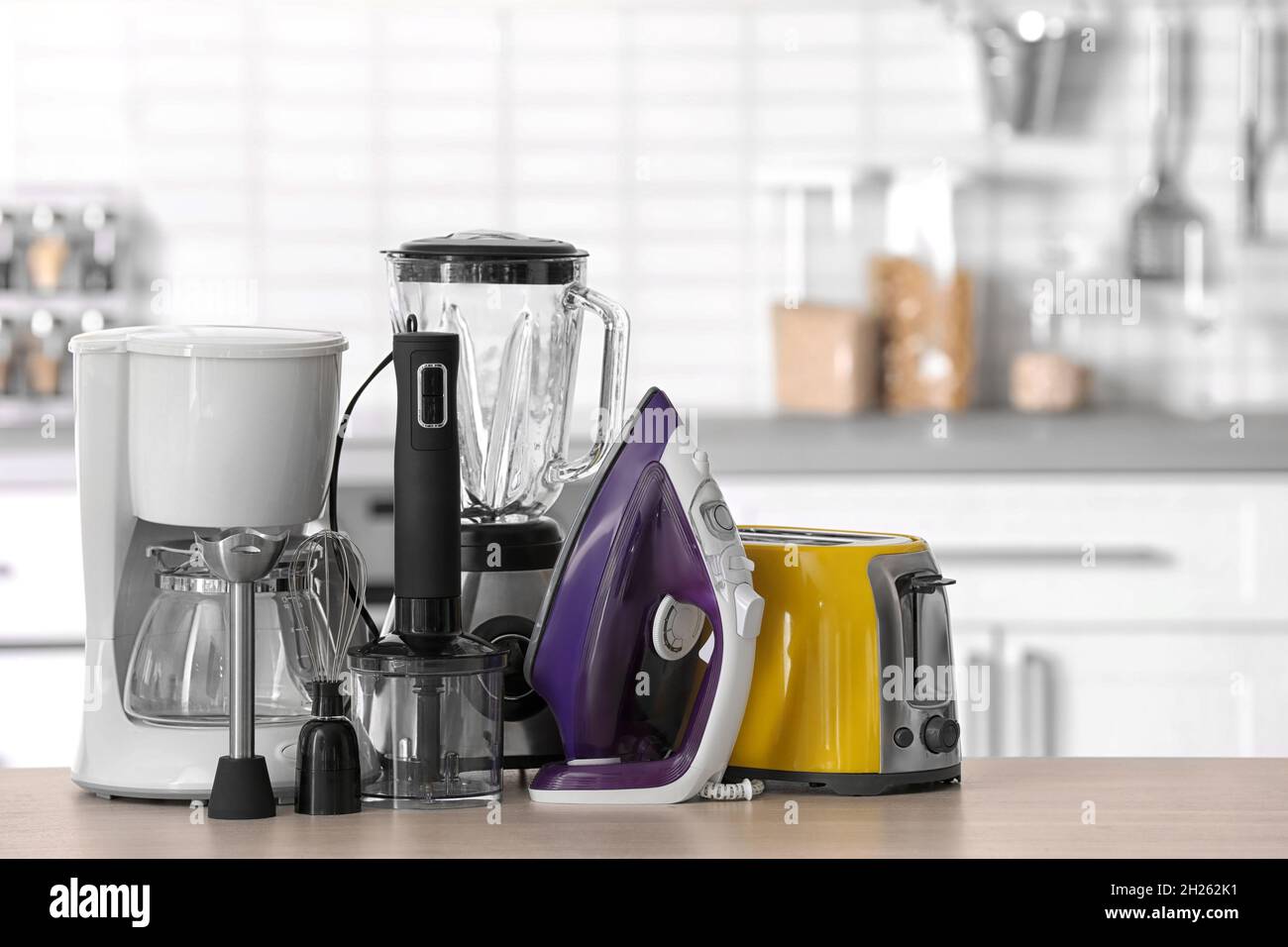 Household and kitchen appliances on table against blurred background ...