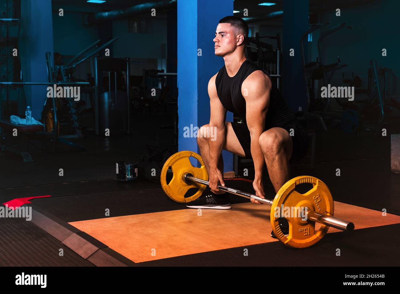 A young man lifts a barbell. Correct body position when lifting weights ...