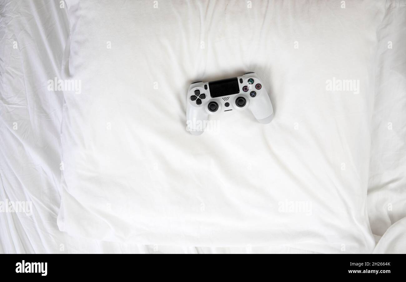 Closeup image top view game controller, lying on white sheets of bed at ...