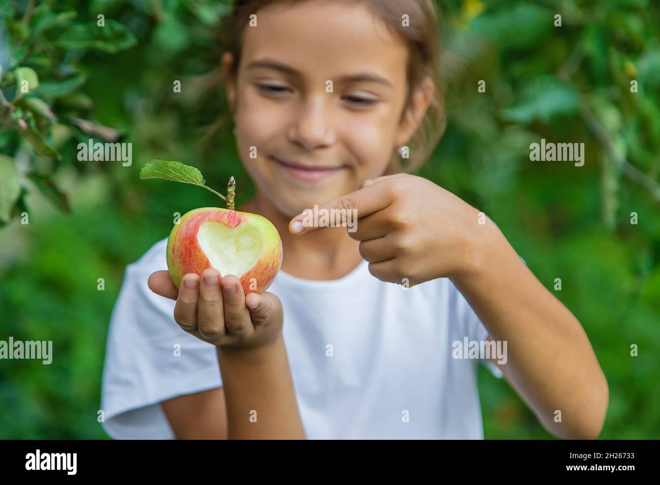The child eats an apple in the garden. Selective focus. Kid Stock Photo ...