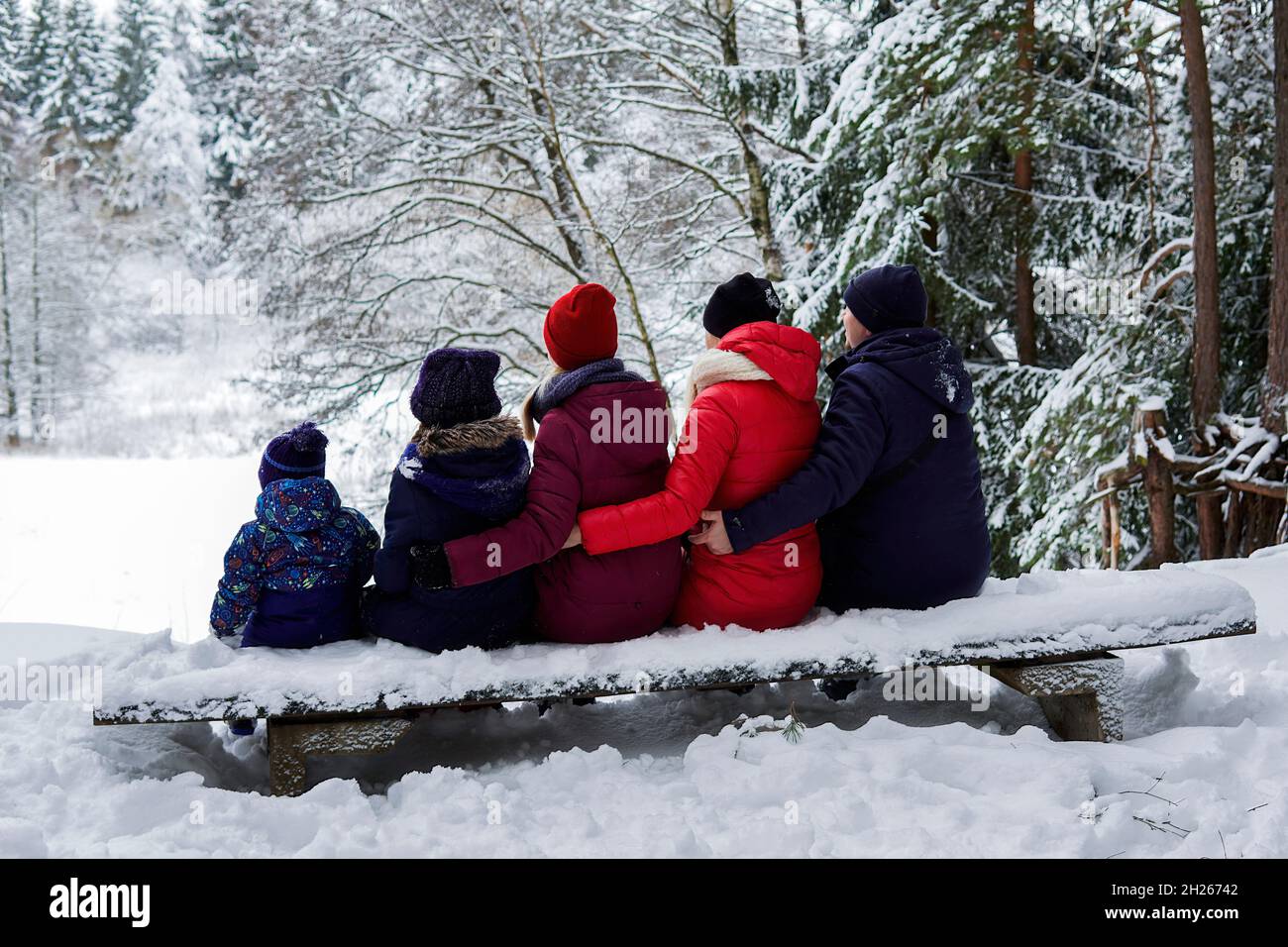 big family, parents and three children are sitting on a bench in a ...