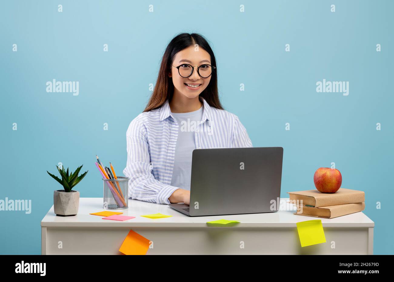 Happy asian lady using laptop while learning online at desk over blue ...
