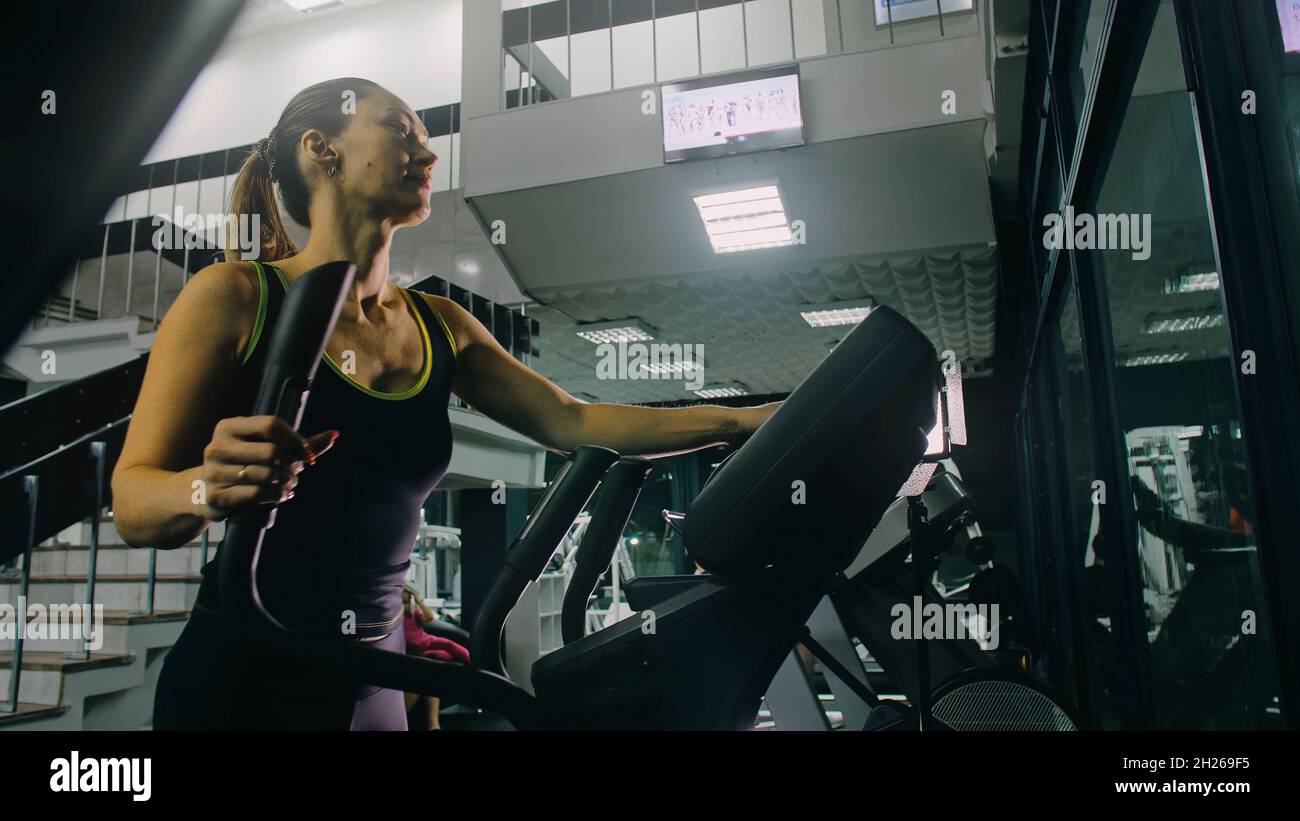 Fit Athletic Woman Exercising on an Elliptical Machine. Muscular Women ...