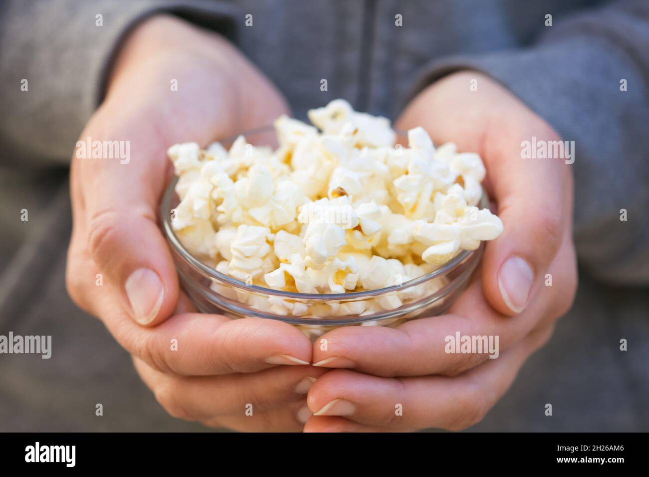 Popcorn in a glass bowl in woman's hands Stock Photo - Alamy