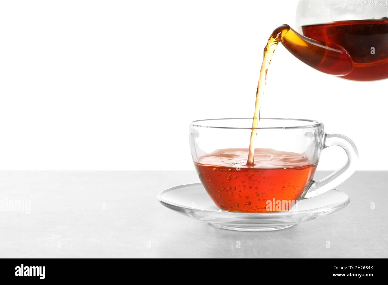 Pouring hot tea into glass cup on white background Stock Photo - Alamy