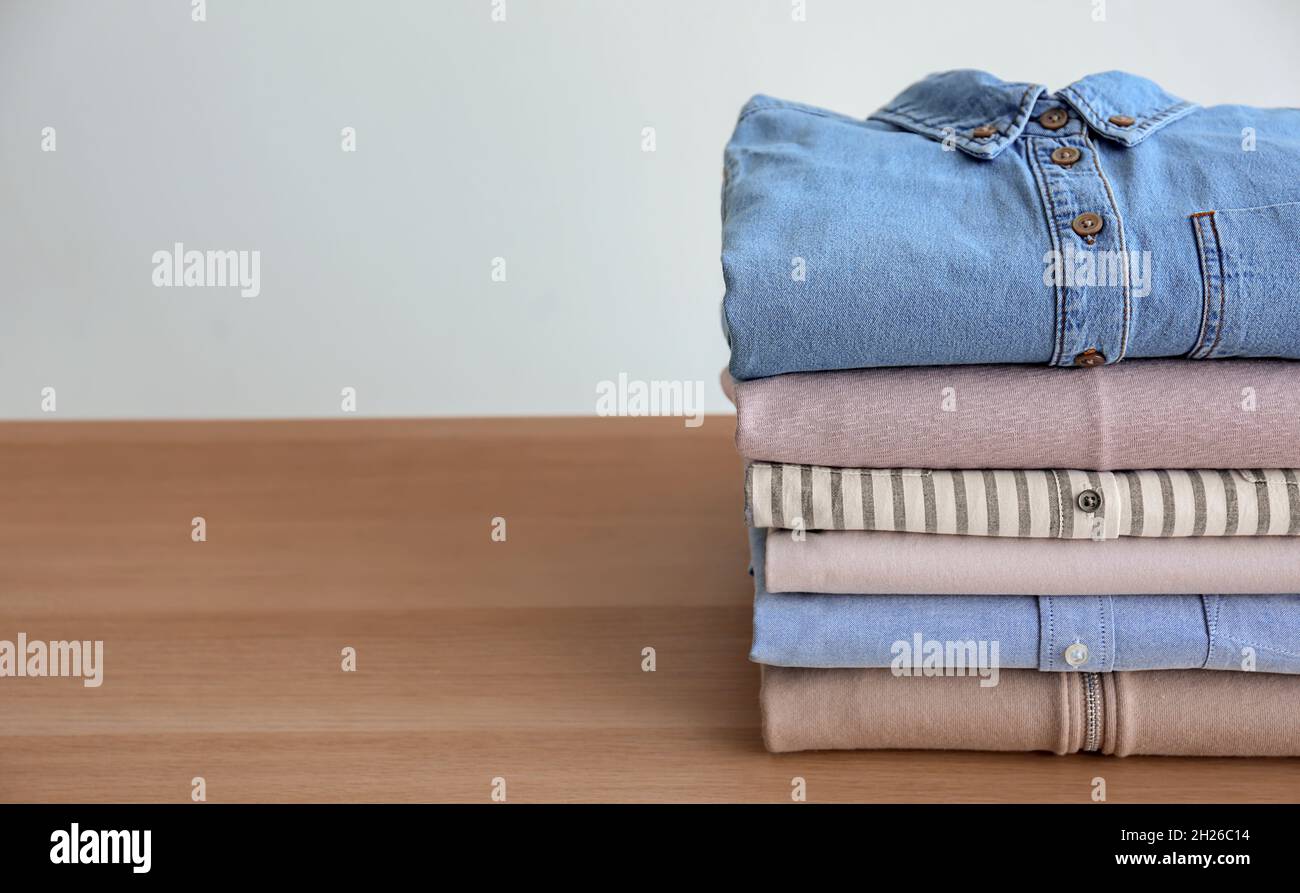 Stack of clothes on table against light background Stock Photo - Alamy