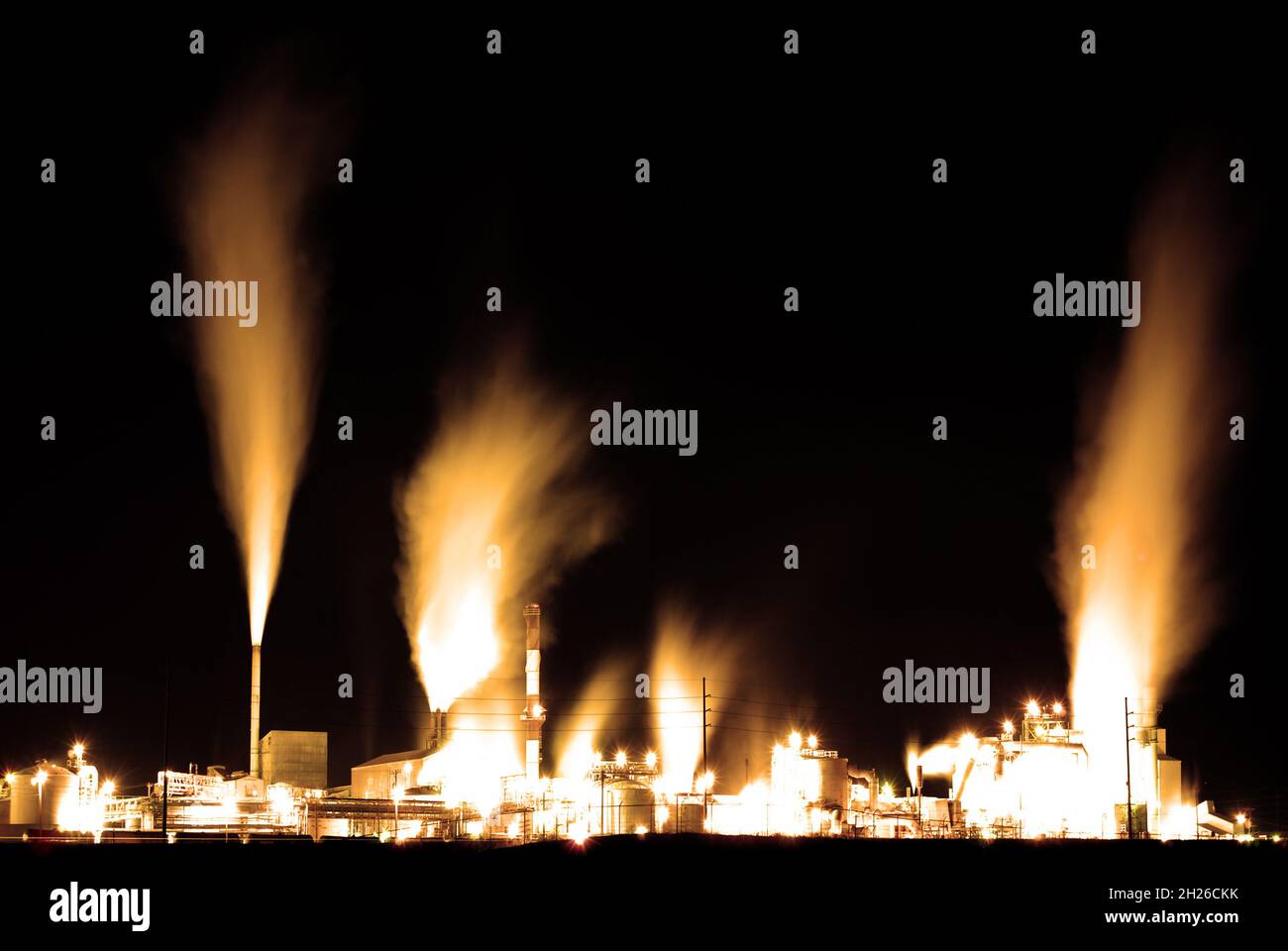 Old factory pumping out pollution and steam through smokestack at night ...