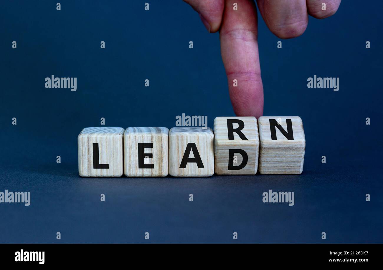 Learn and lead symbol. Businessman turns wooden cubes, changes the word 'learn' to 'lead ...