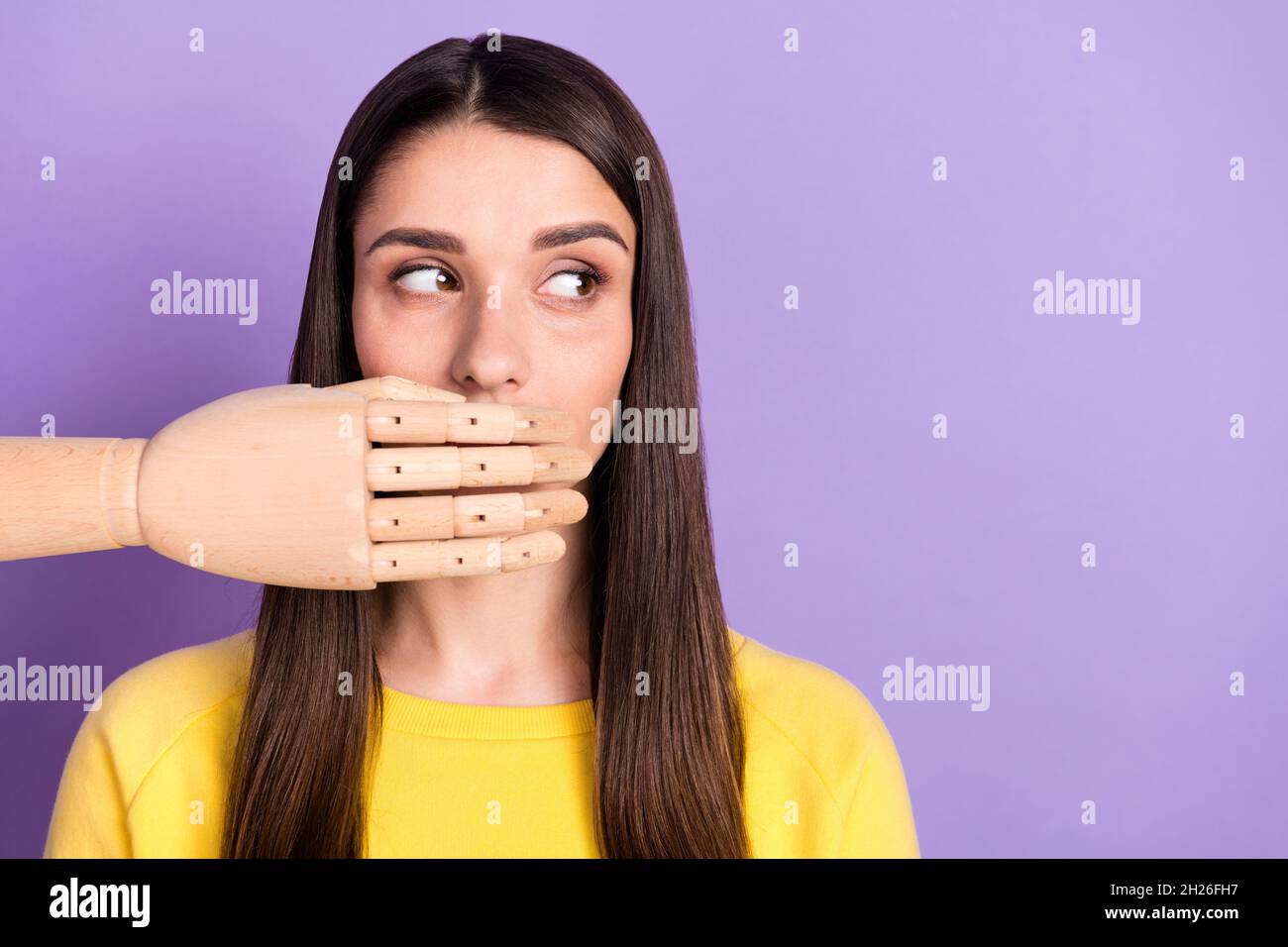 Portrait of attractive long-haired girl fake doll hand closing mouth ...