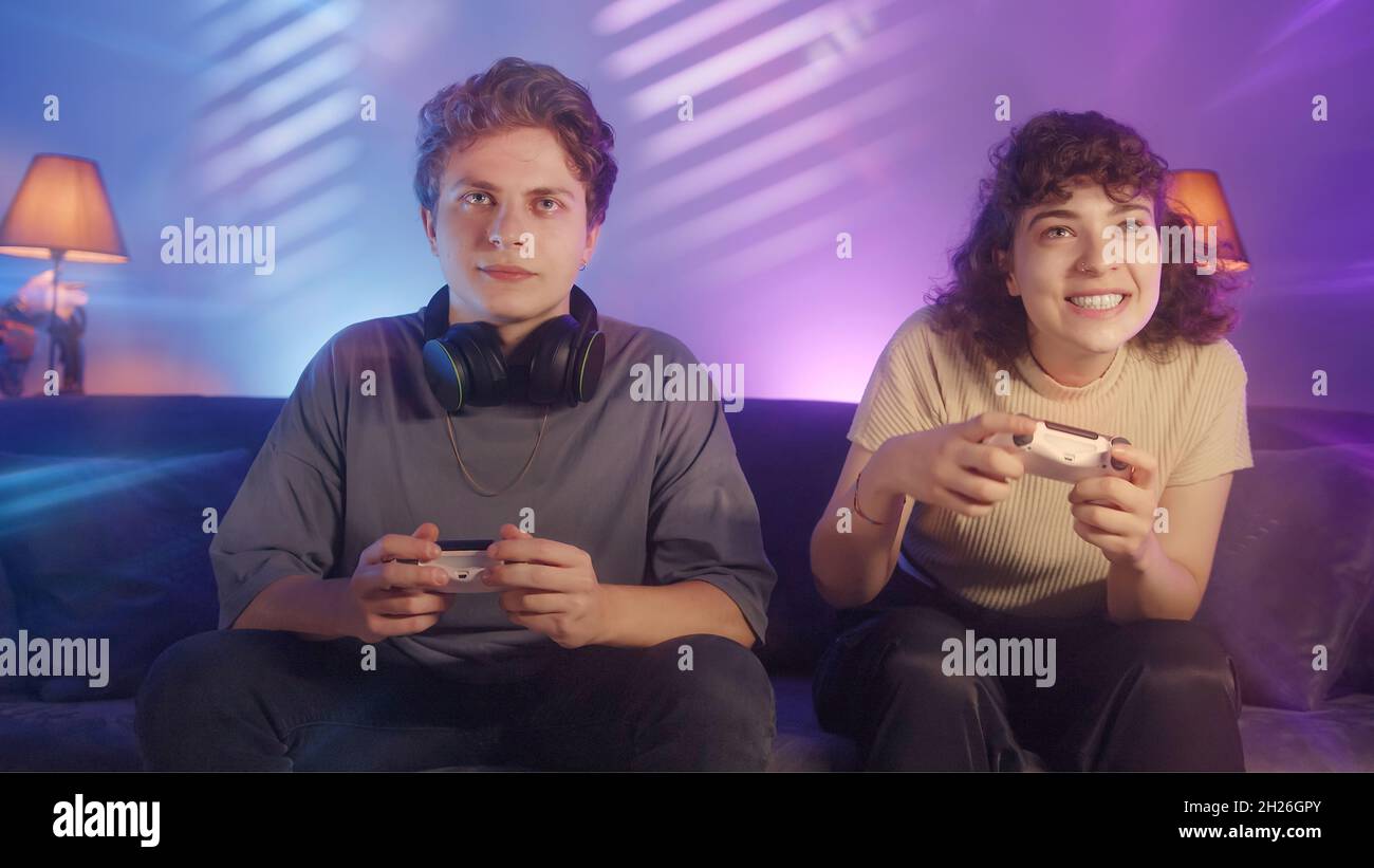 Cute competitive couple gamers sitting on couch and playing a video ...