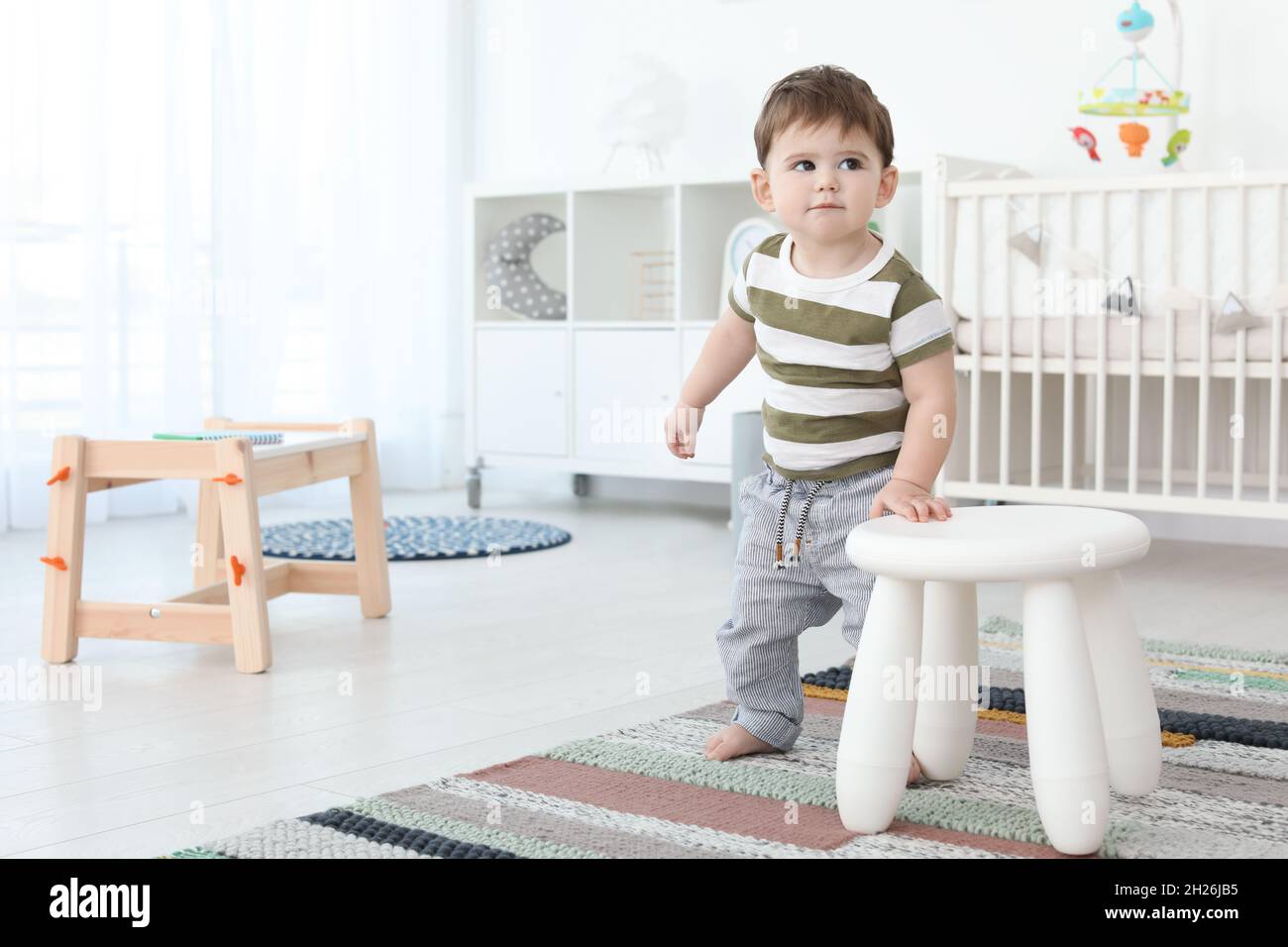 Cute baby holding on to stool at home. Learning to walk Stock Photo - Alamy