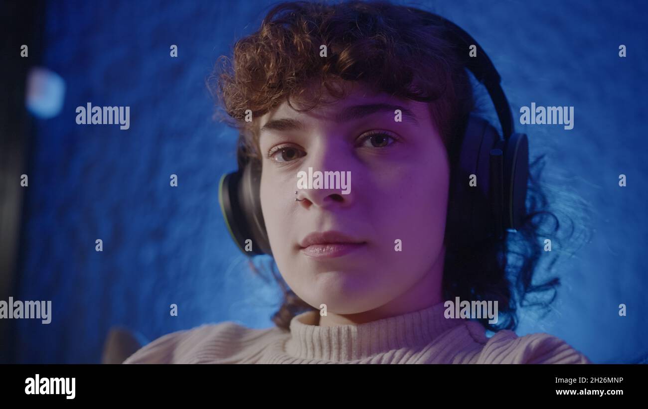 Portrait of cute curly-haired gamer girl looking at camera. Young ...
