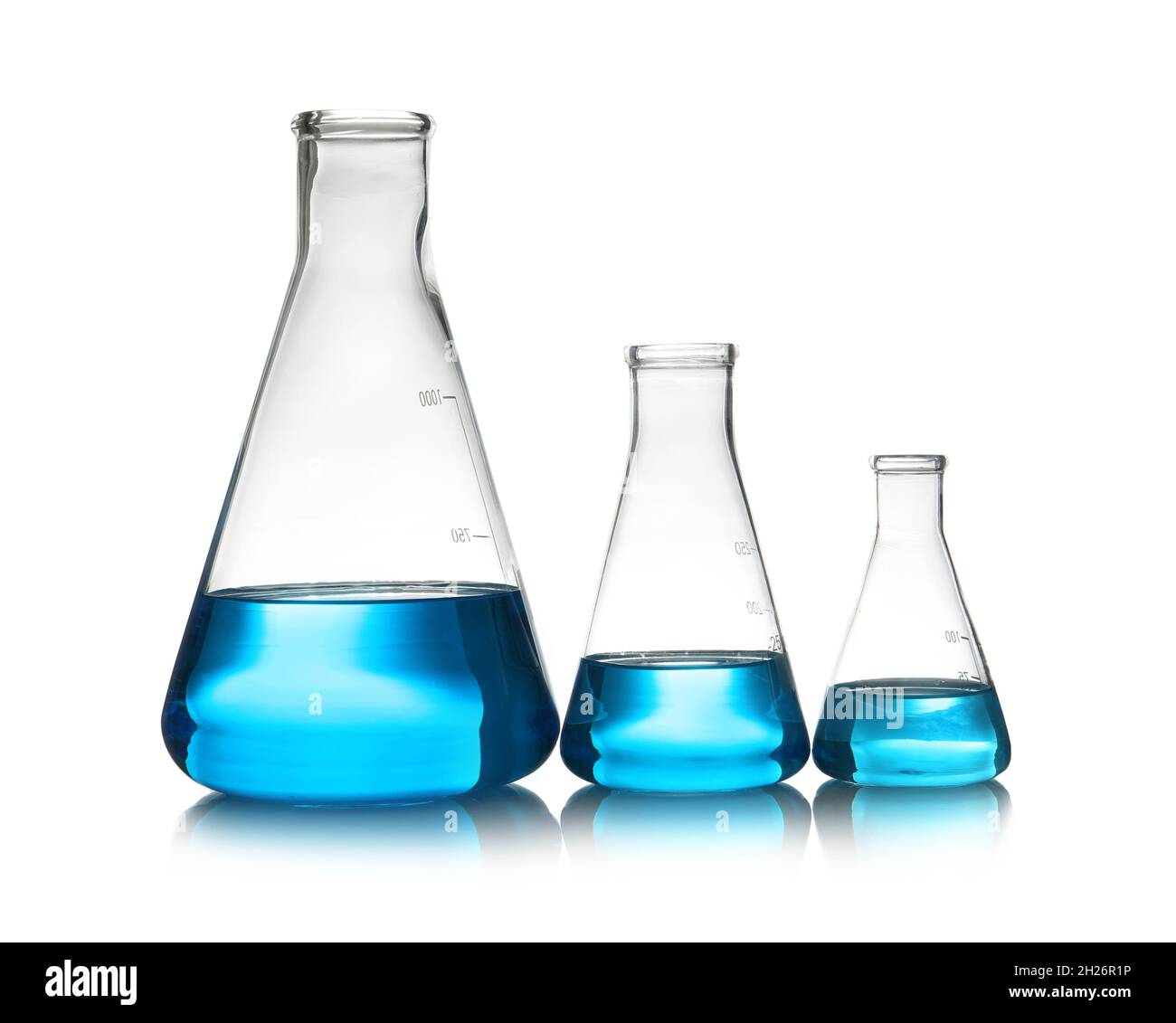 Conical flasks with liquid on table against white background ...