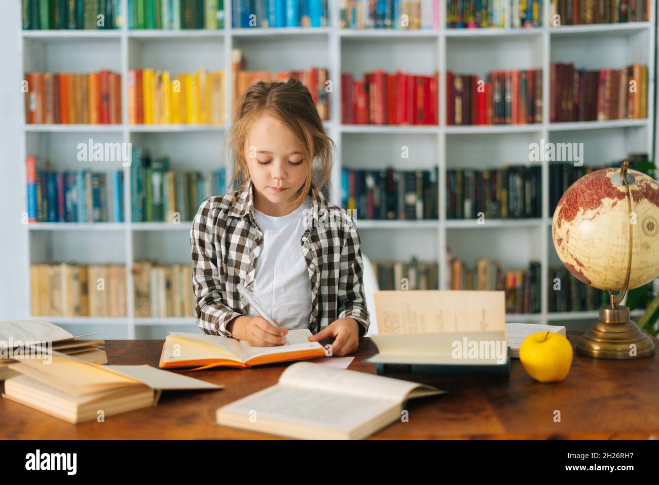 Front view of attractive pupil school girl kid doing homework writing ...