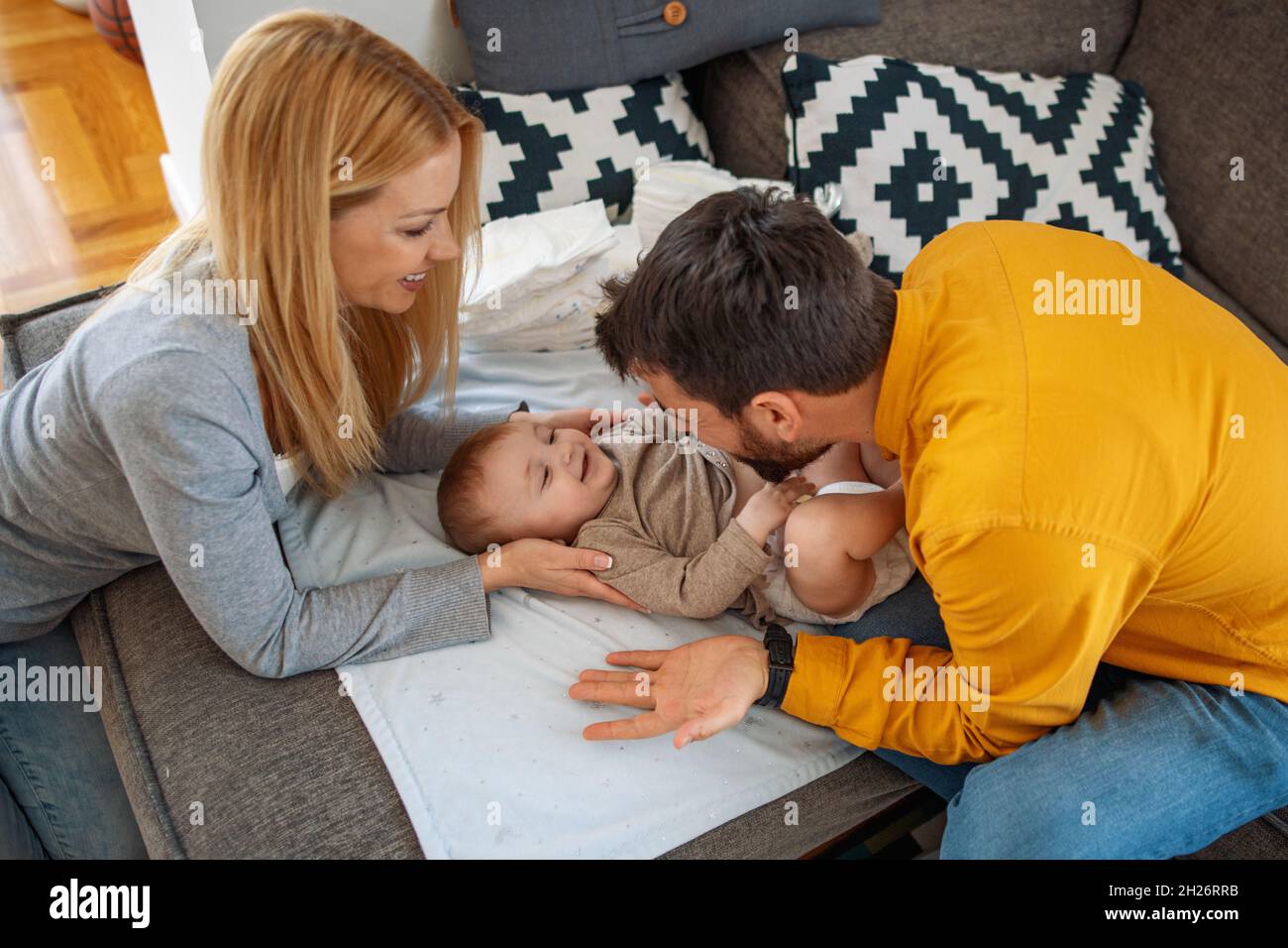 Smiling father has fun with baby while changing his nappy at home Stock ...