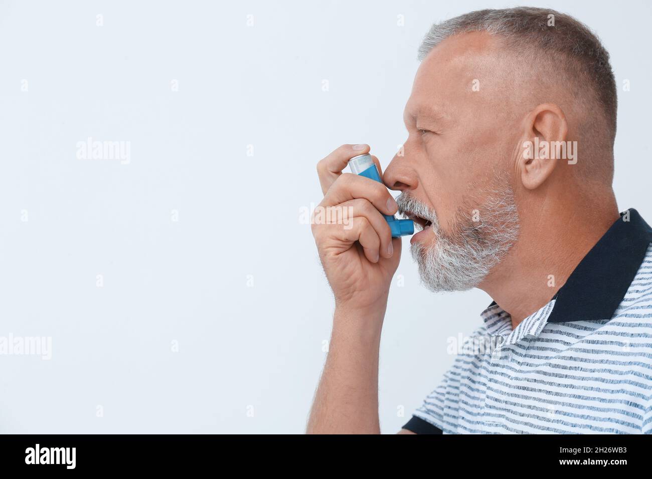 Man using asthma inhaler on white background Stock Photo - Alamy