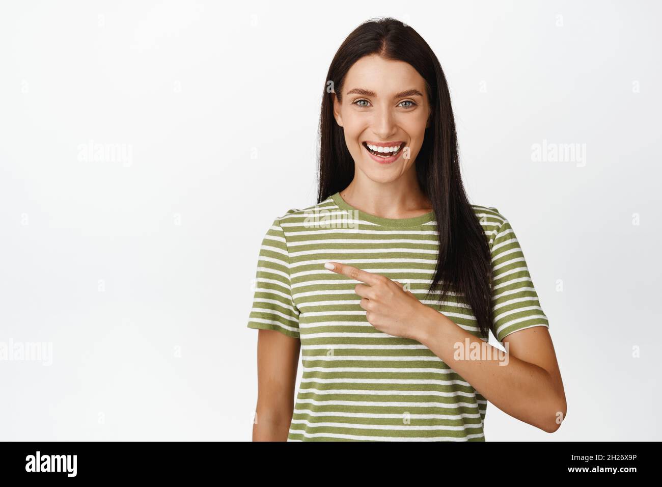 Portrait of attractive young woman pointing left, looking happy ...