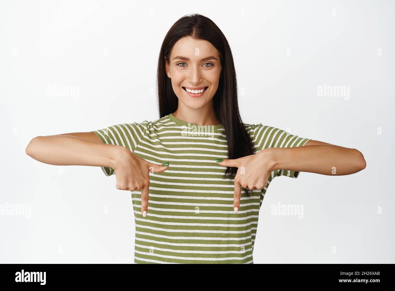 Smiling adult woman pointing fingers down, showing advertisement below ...