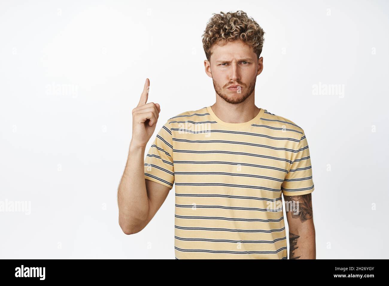 Suspicious blond guy squinting, pointing finger up at something ...