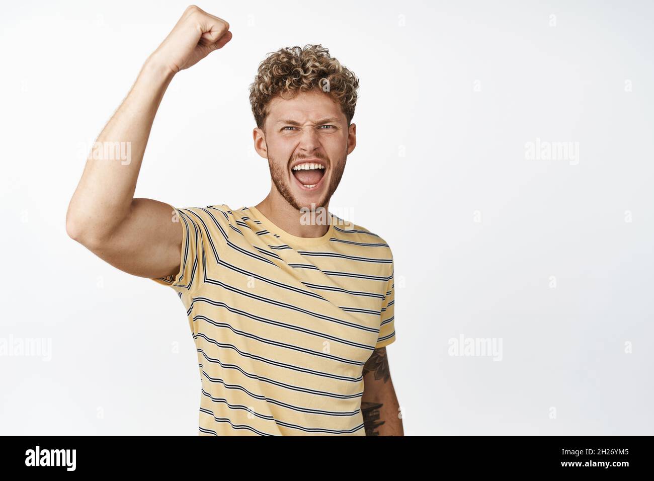 Motivated blond handsome guy rooting, protesting, raising clenched fist ...