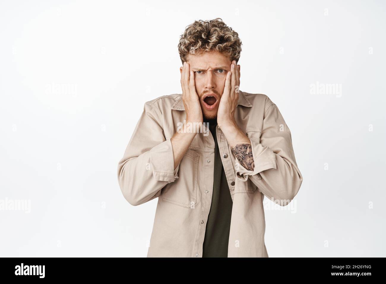 Shocked blond man receives bad news, reacting to shocking terrible ...