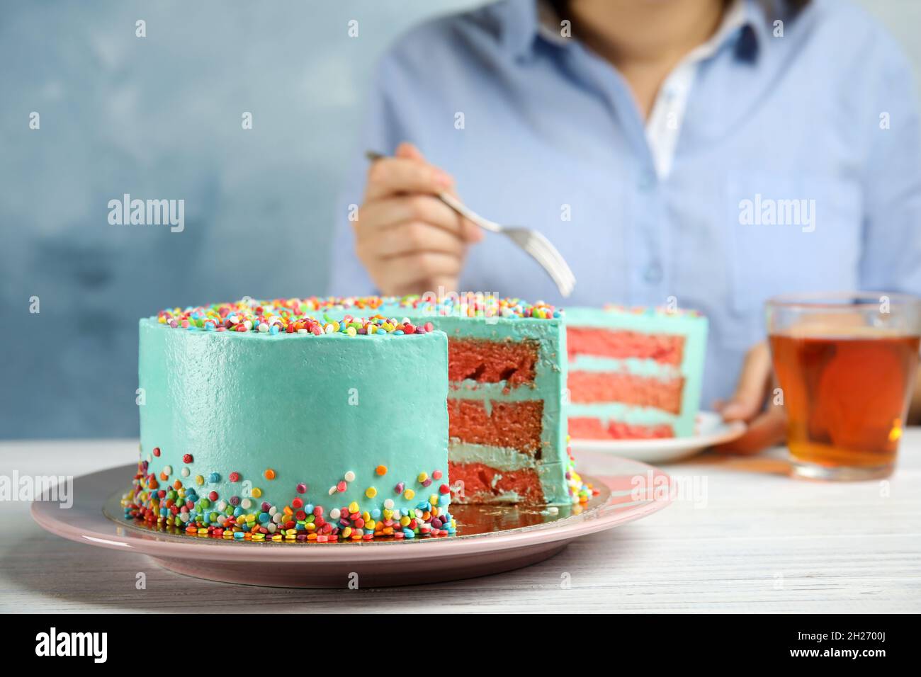 Cut fresh delicious birthday cake and blurred woman on background Stock ...