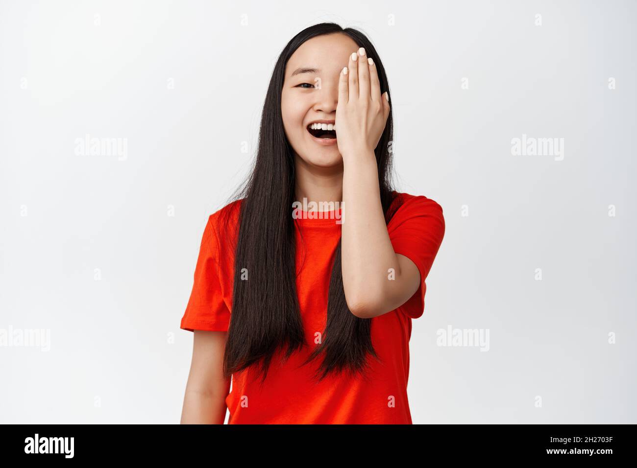 Pretty asian woman covers one side of face and smiling, laughing ...
