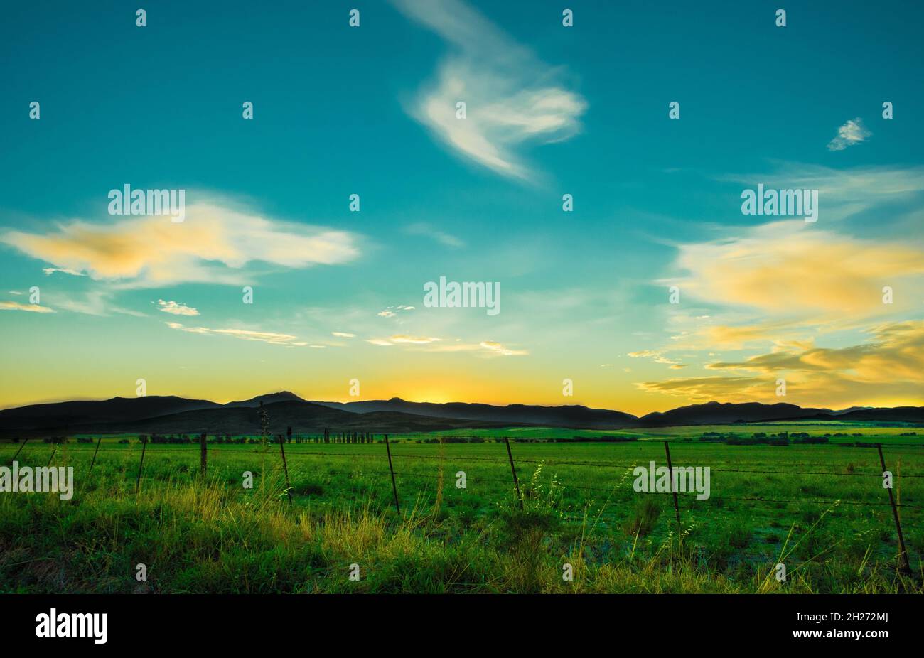 Beautiful pasture field below the mountain against a cloudy sunset sky ...