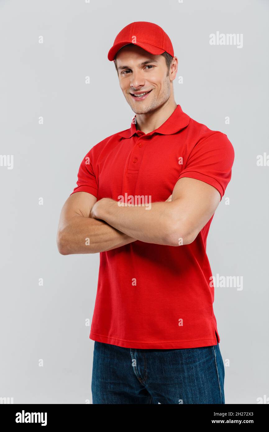 Young delivery man wearing uniform smiling while posing with arms ...