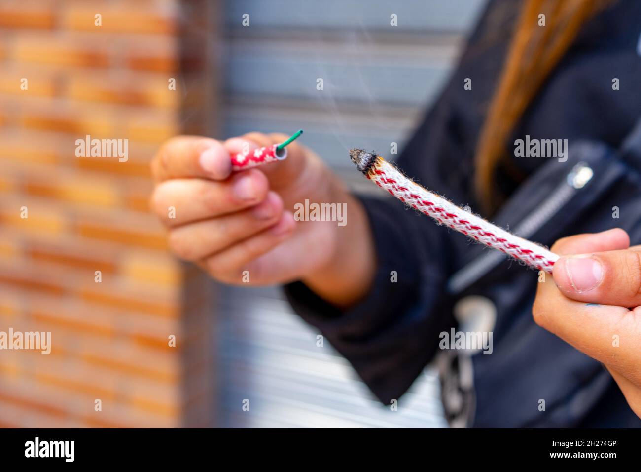 Close up of man hand lighting up a firecrackers in a burred background ...